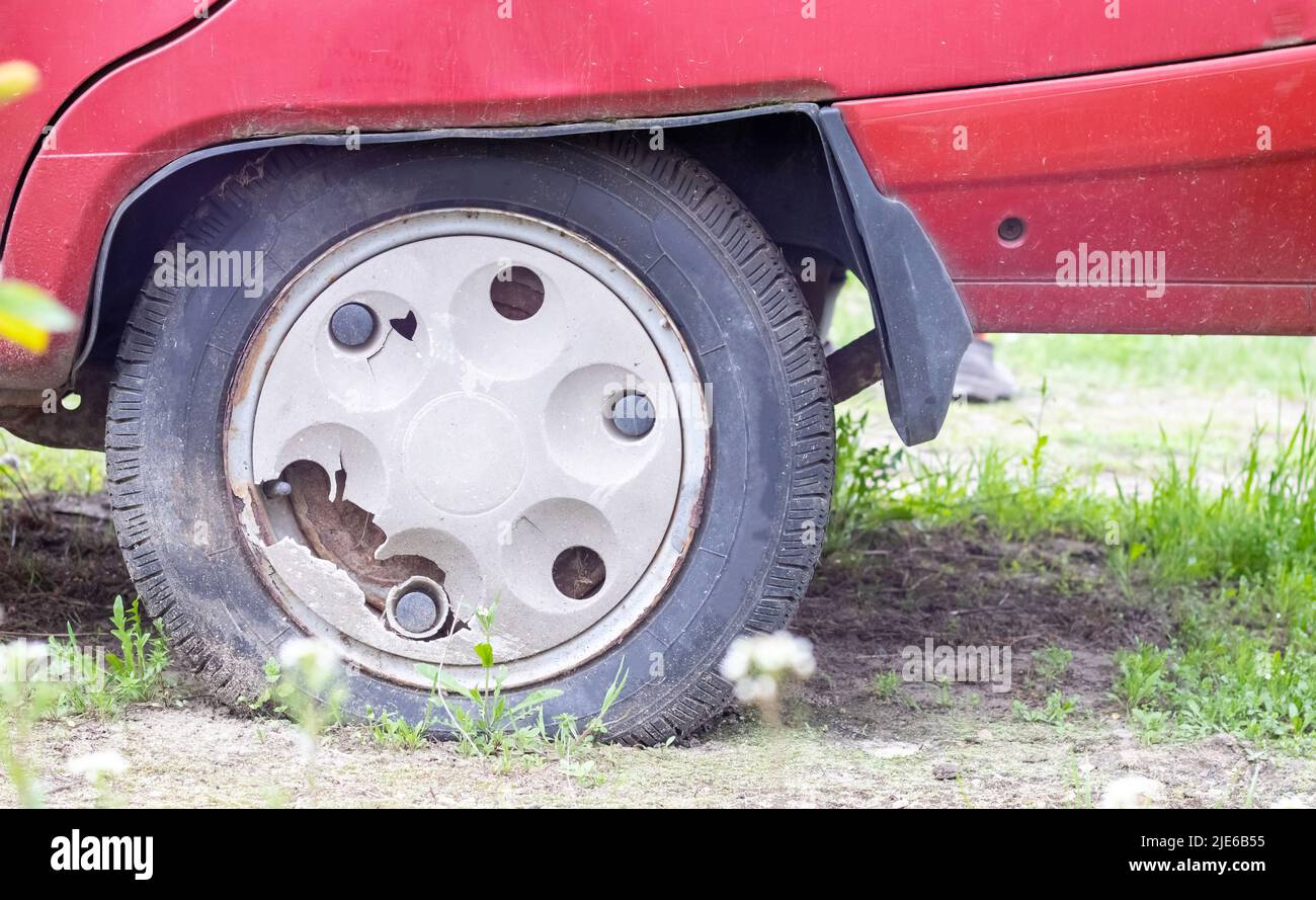 Weathered car wheel with dirt and grime. Rusty abandoned car in the ...