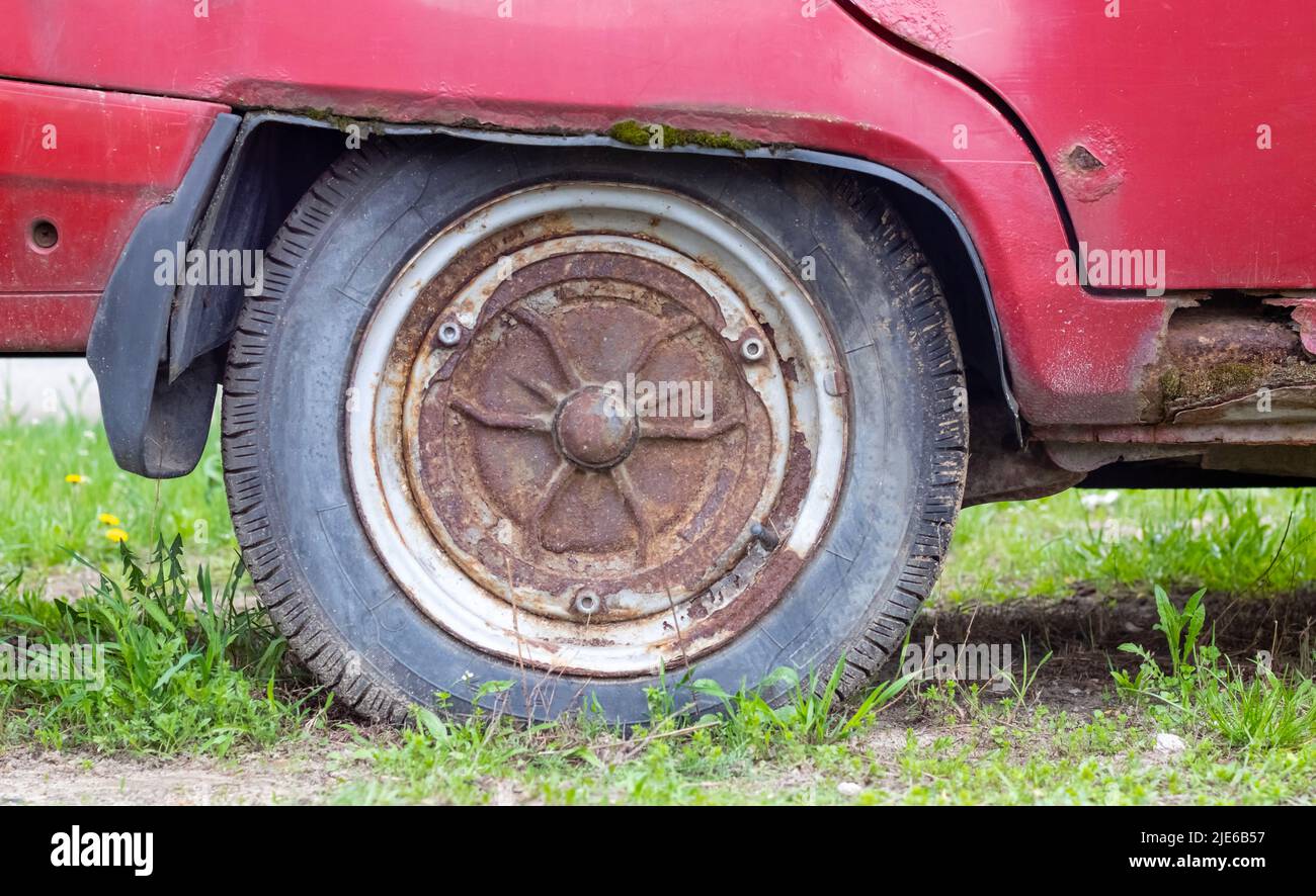 Weathered car wheel with dirt and grime. Rusty abandoned car in the ...