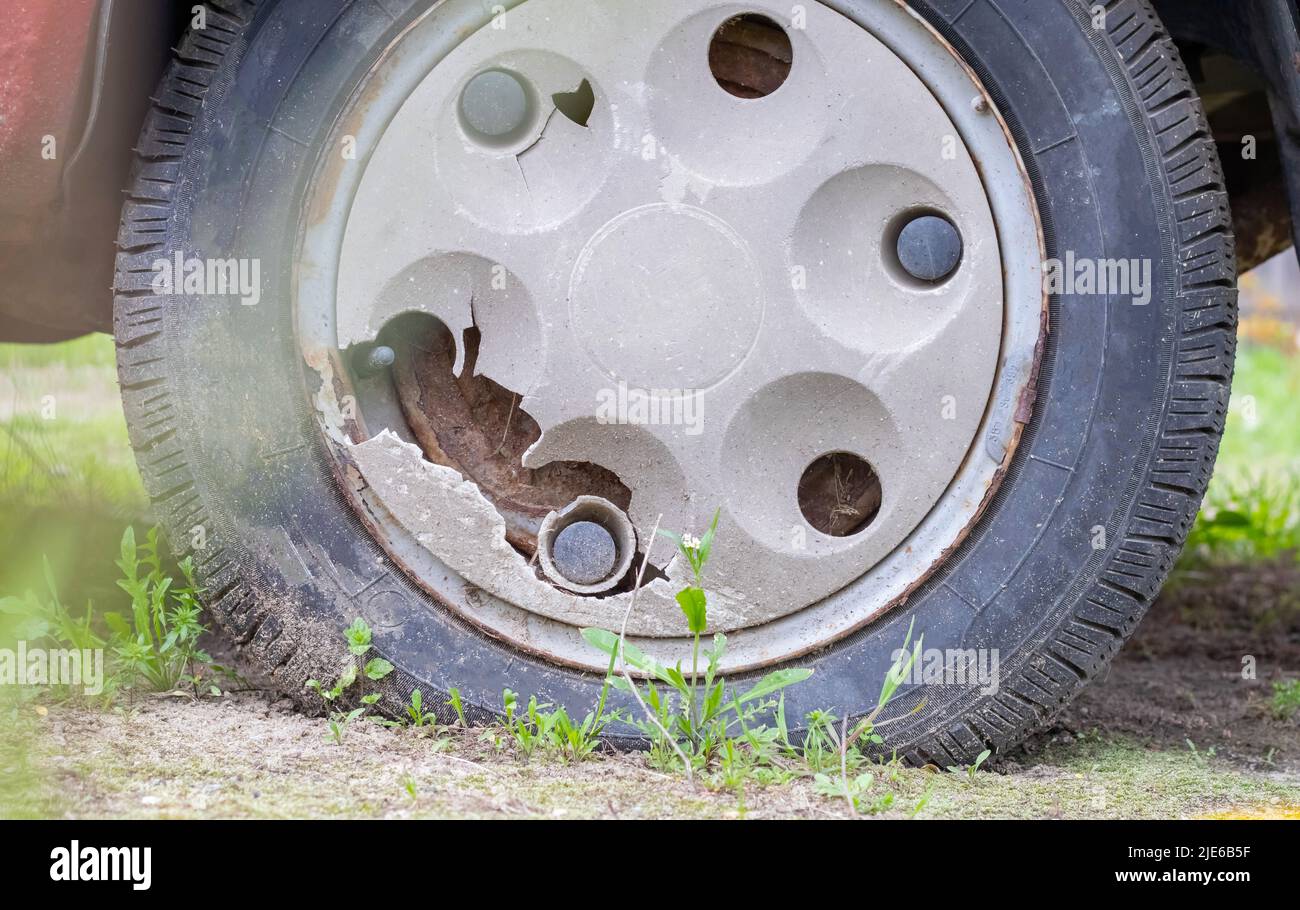 Weathered car wheel with dirt and grime. Rusty abandoned car in the ...
