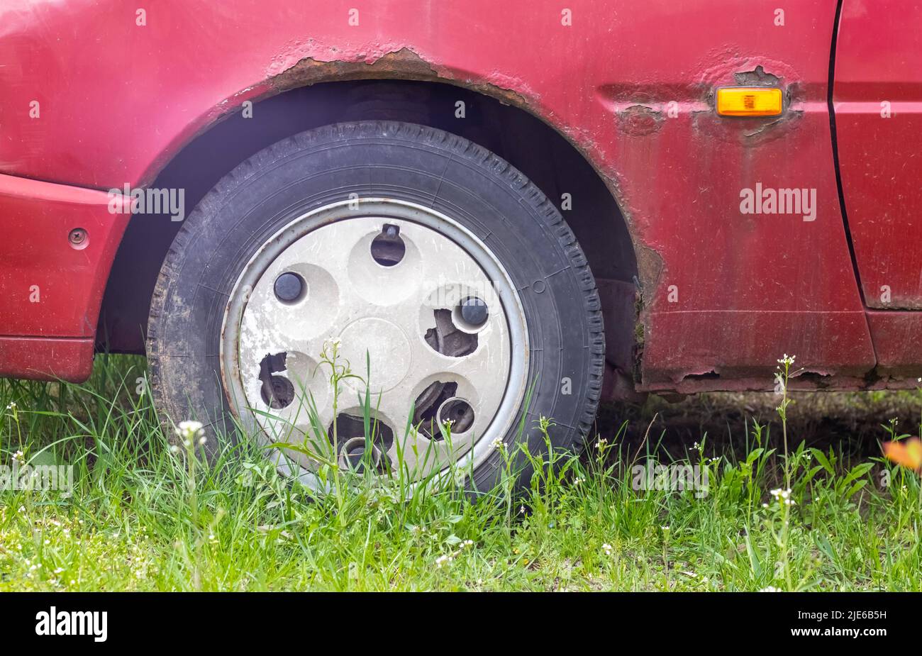 Weathered car wheel with dirt and grime. Rusty abandoned car in the ...