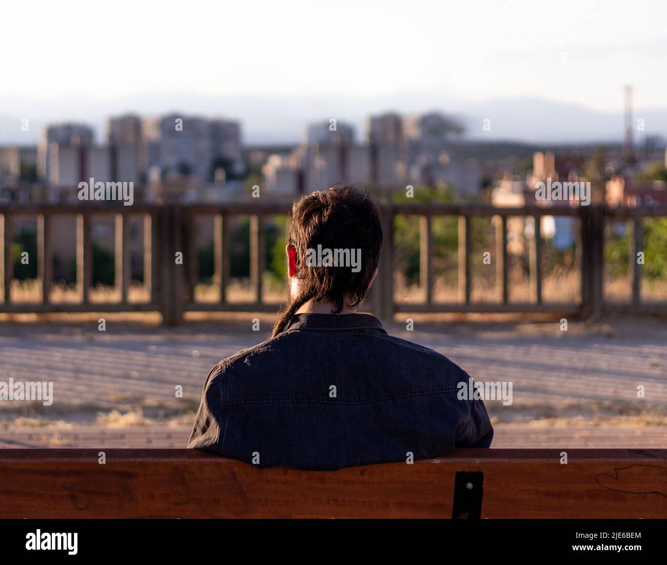 Alone pensive man looking at the sunset in the city sitting on a bench ...