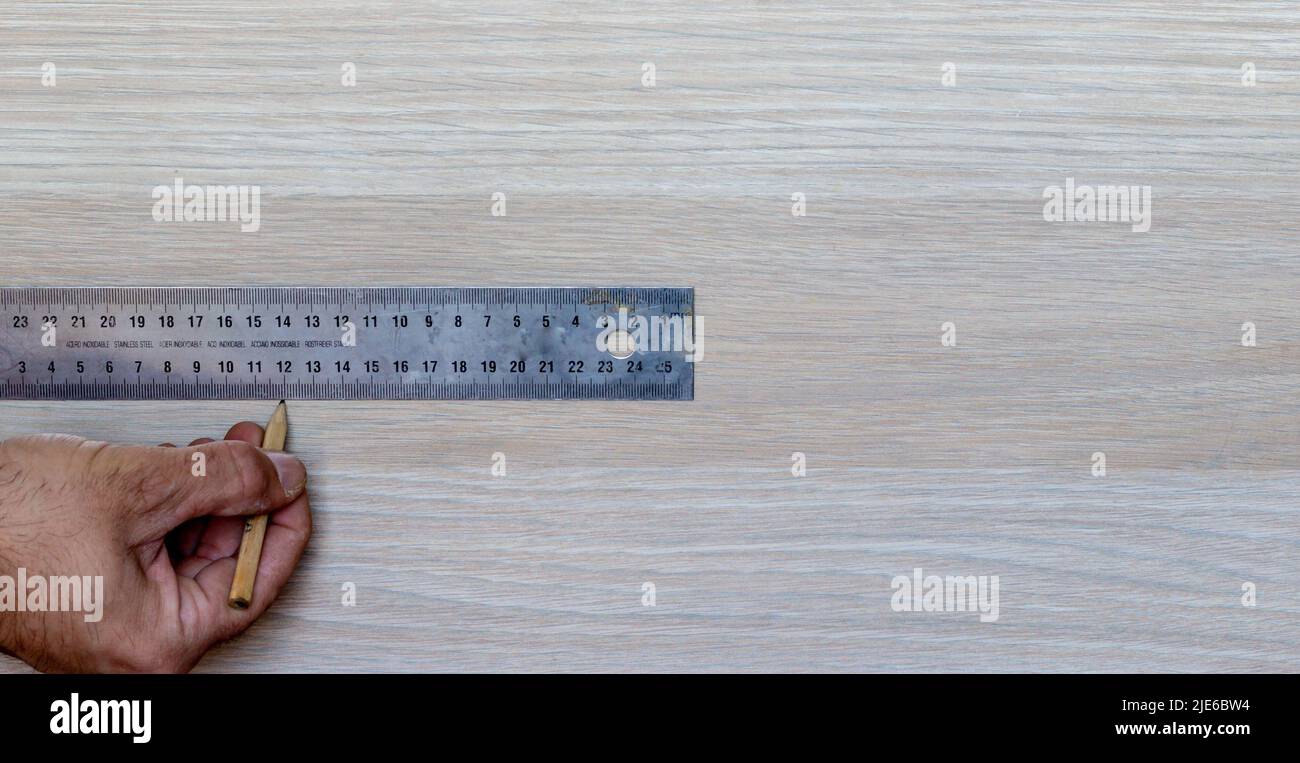 Working with the hands. Carpenter measuring a piece of furniture with a ...