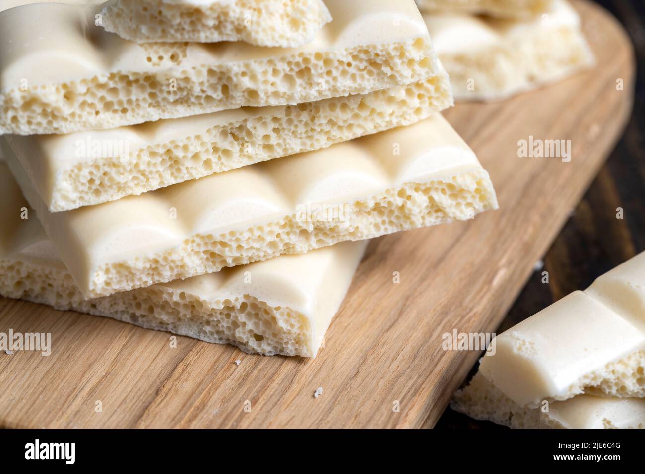 white porous chocolate on a wooden table, pieces of white porous ...
