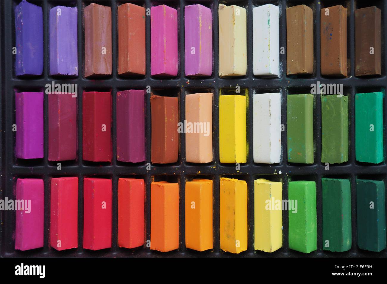 Set of colored pastels laid out in a black box. The concept of classes ...