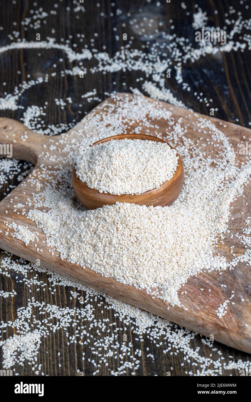 a large amount of white dried sesame seeds in a wooden bowl, sesame ...
