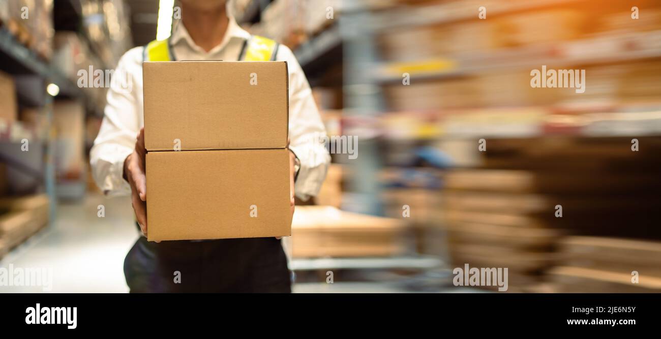 Close-up, workers carrying boxes in a large logistics warehouse ...