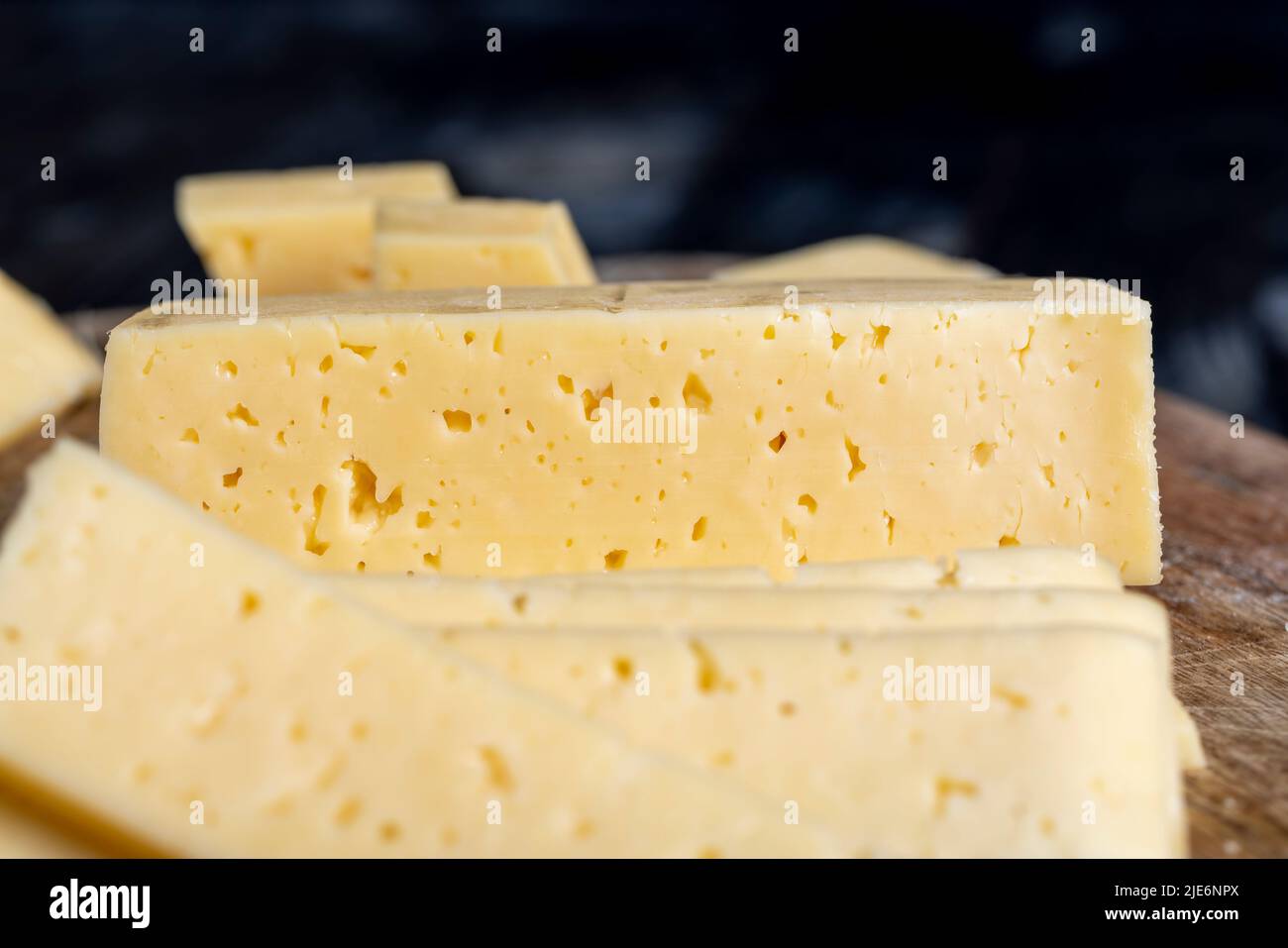 sliced natural cow's milk cheese, fresh yellow milk cheese on a board ...