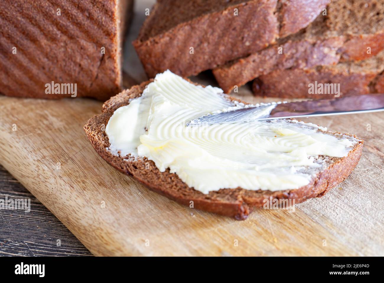 spread butter on black rye bread, slices of black sliced bread with ...