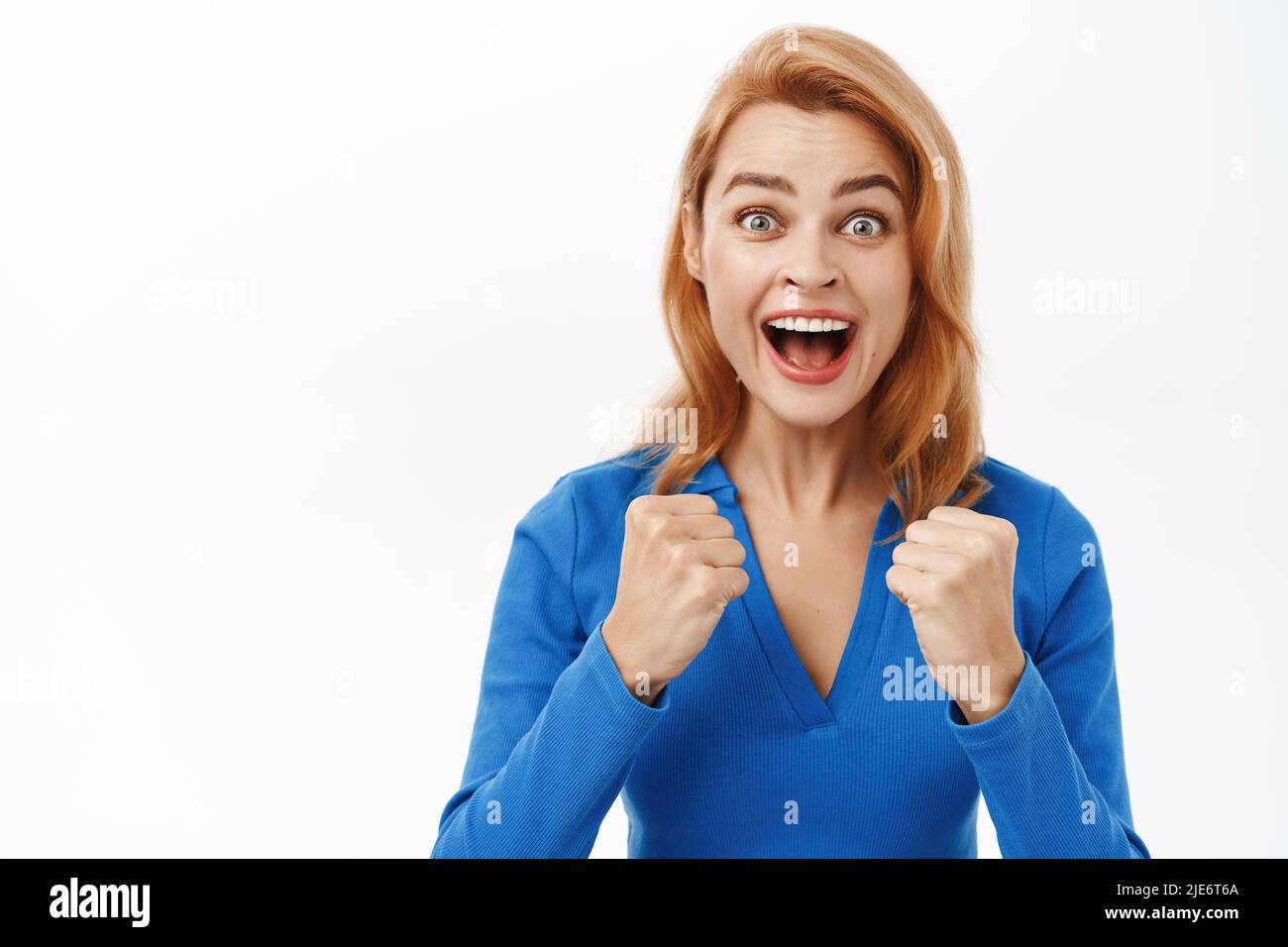 Close up of ecstatic girl, shows fists and looks excited, ready to ...