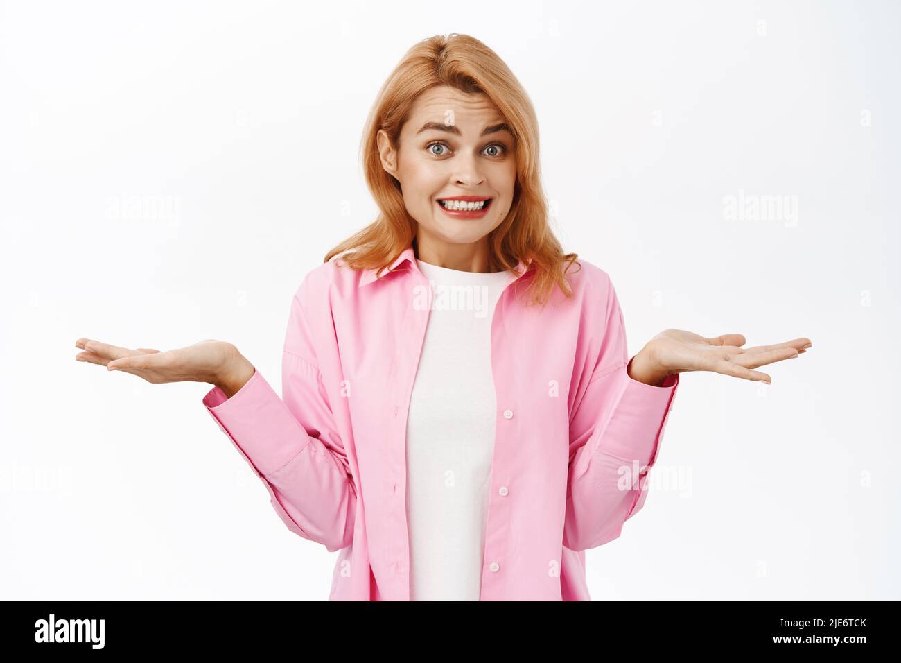Portrait of cute smiling woman shrugging shoulders and empty hands ...