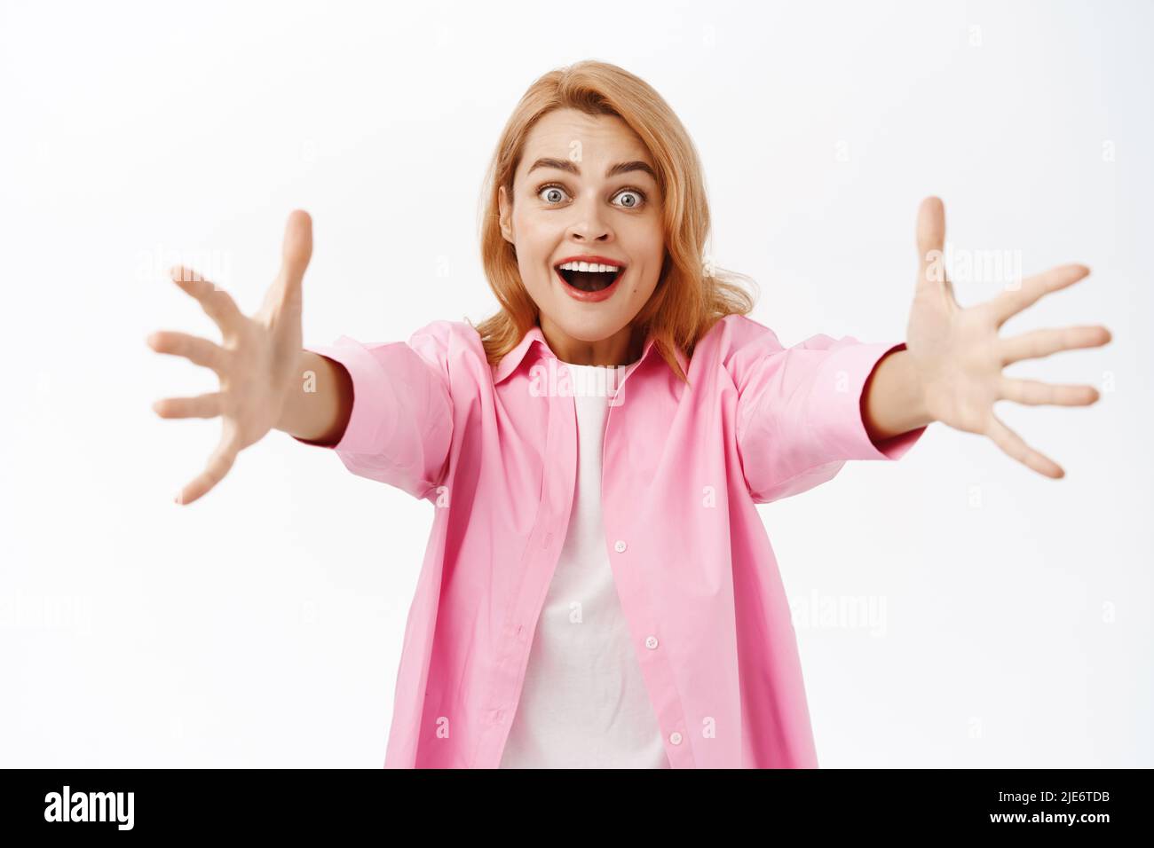 Image of happy young woman reaching her arms for something, grabbing ...