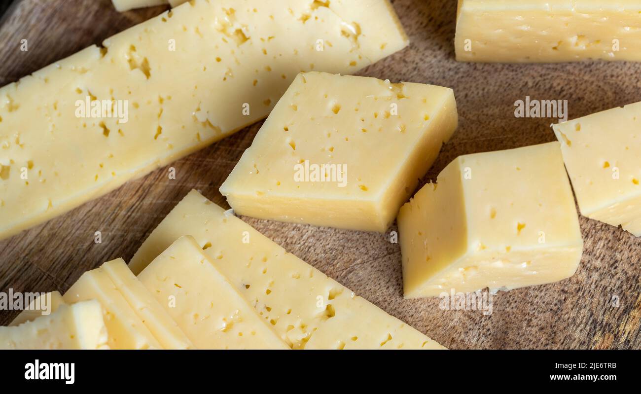sliced natural cow's milk cheese, fresh yellow milk cheese on a board ...