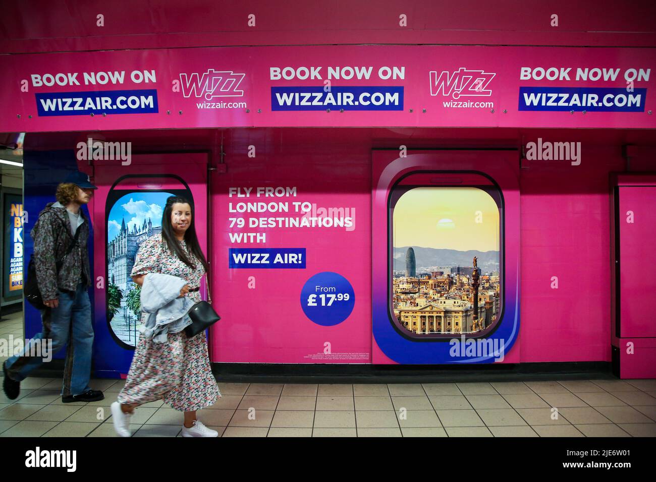 Passengers walk past Wizz Air advert displayed at a tube station Stock ...