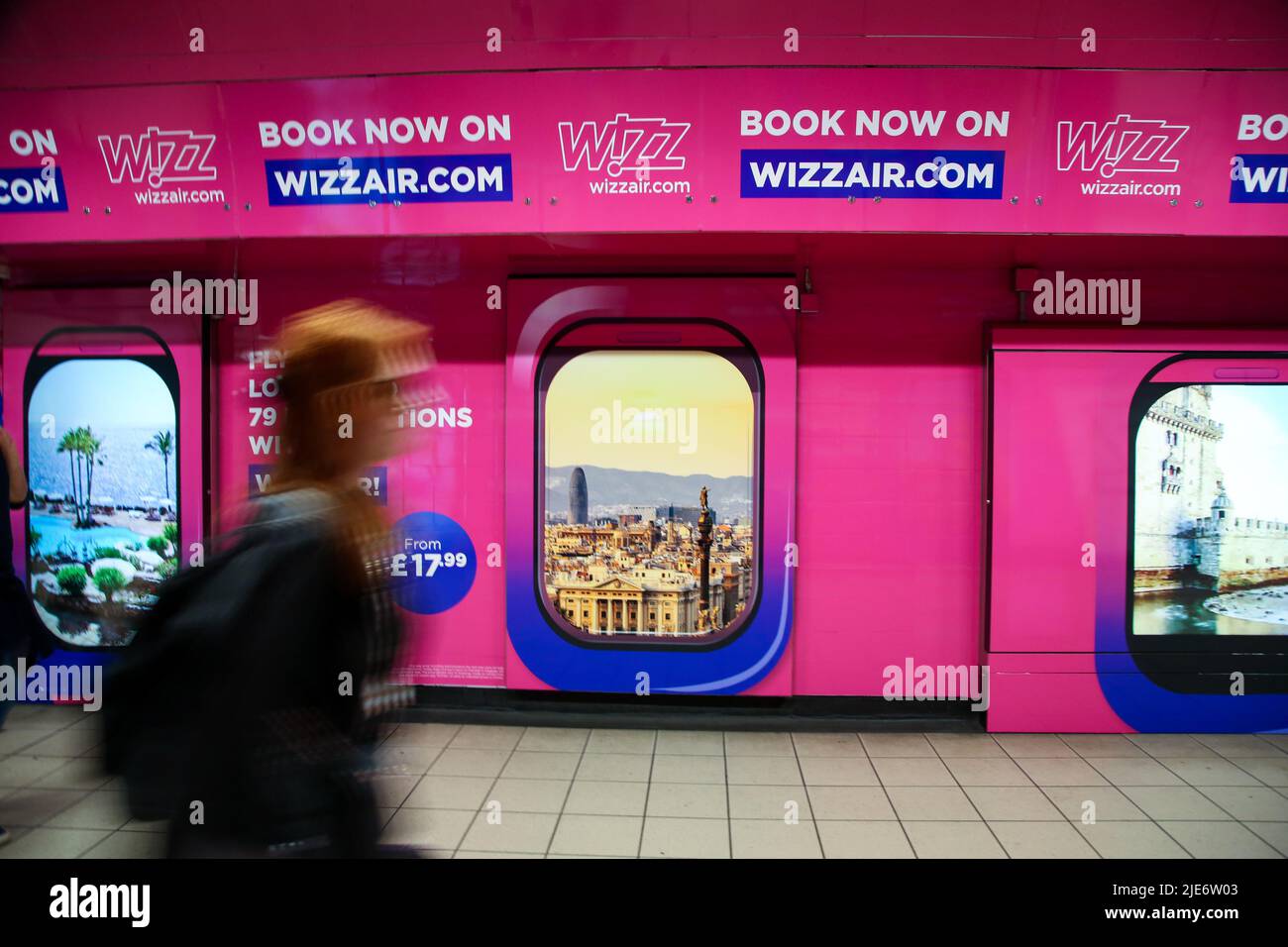 A woman walks past Wizz Air advert displayed at a tube station Stock ...