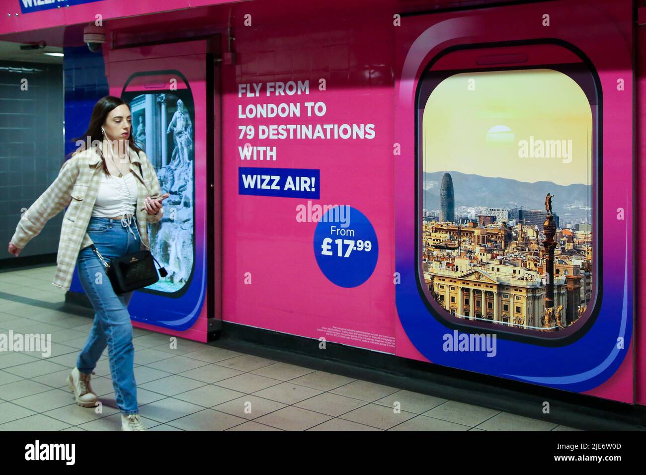 A woman walks past Wizz Air advert displayed at a tube station Stock ...