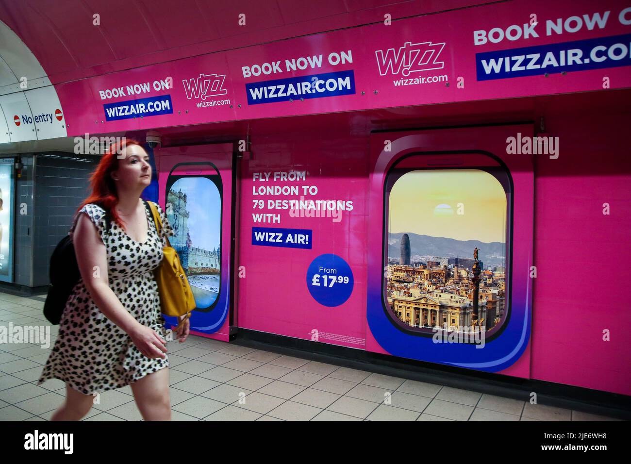 London, UK. 25th June, 2022. A woman walks past Wizz Air advert ...