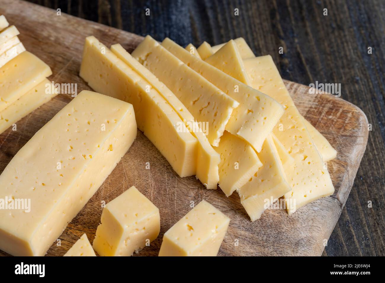 sliced natural cow's milk cheese, fresh yellow milk cheese on a board ...