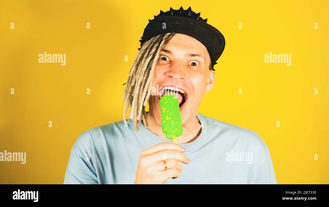 Young funny man in black cap licking ice cream. Excited male with ...