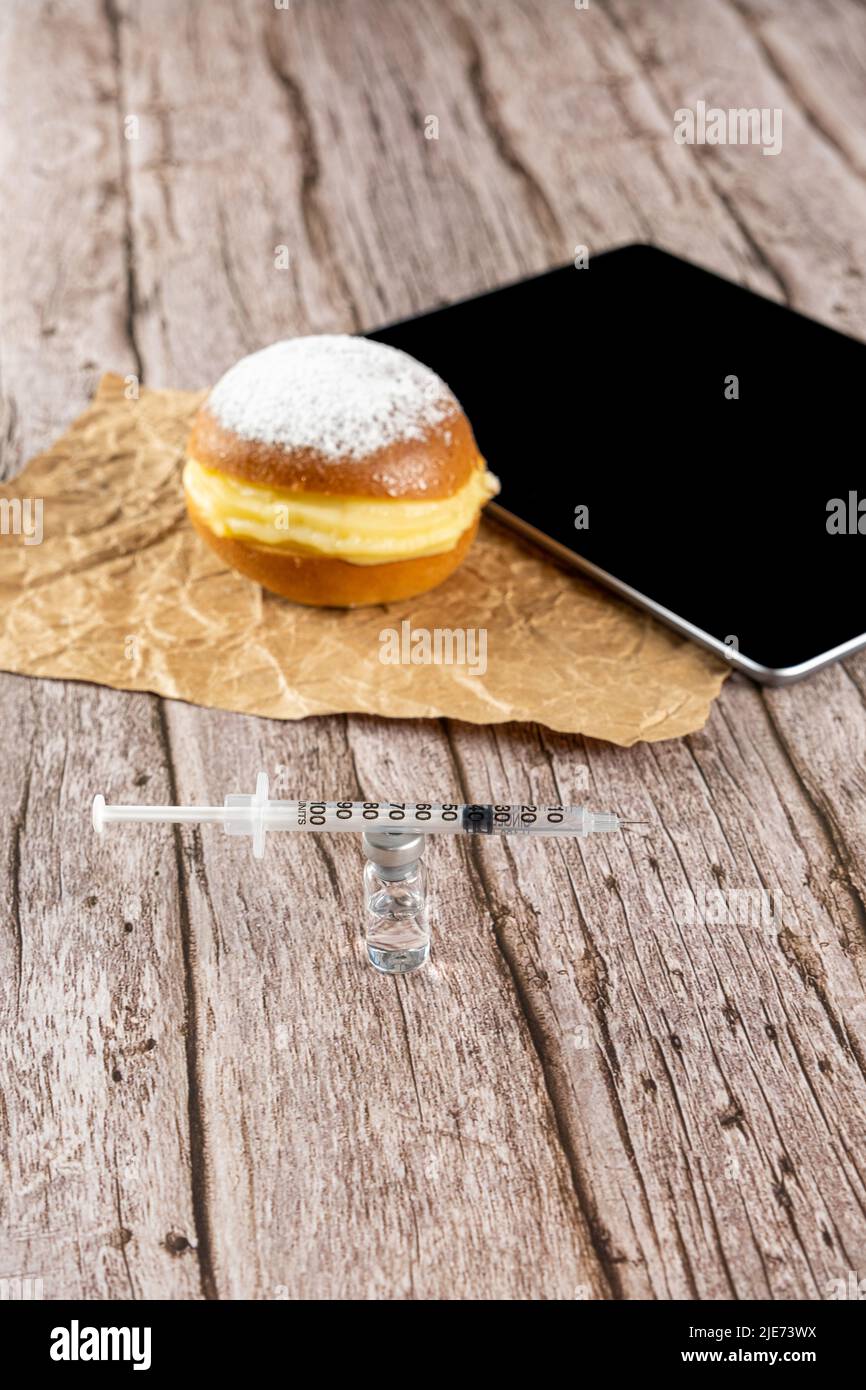 Syringe on an insulin ampoule next to a Brazilian cream doughnuts and a ...