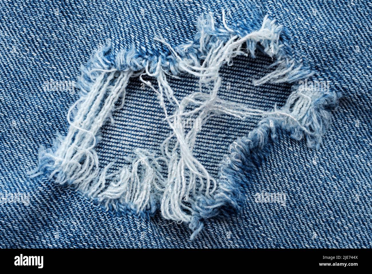 Hole in denim close-up. Ripped blue jeans Stock Photo - Alamy
