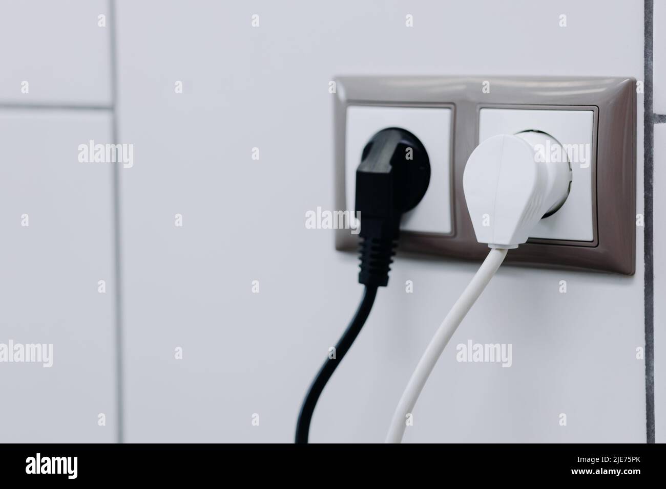 White and black cables in a socket on a white wall. Close up. High ...