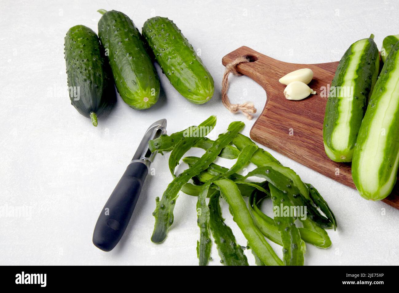 Fresh cucumbers with skin and peeled on a brown wooden cutting board on ...
