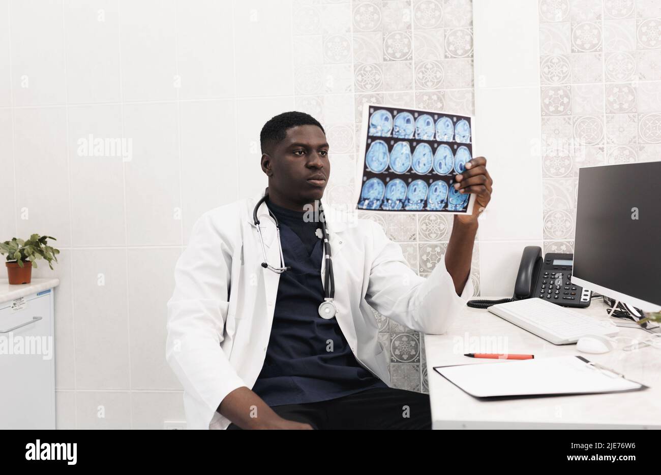 Close-up of an African-American doctor in a white coat looking at an X ...