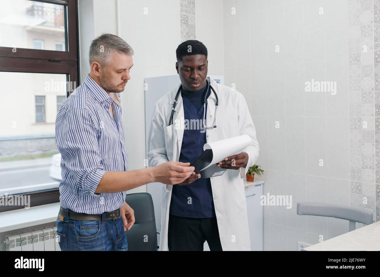A young African-American doctor consultations with a patient in a ...