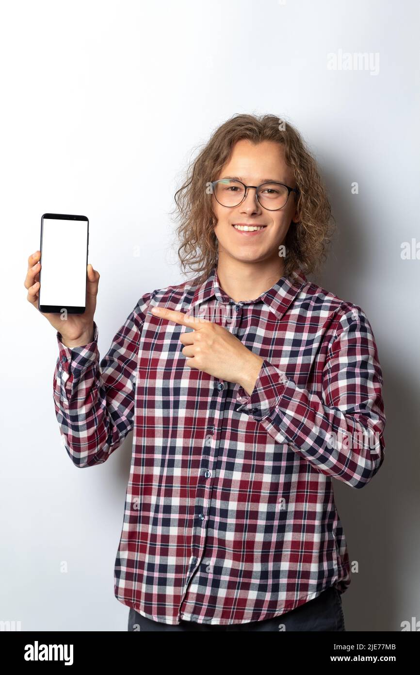 Handsome young man holding smartphone with white blank screen. The guy ...