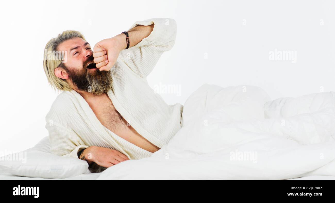 Handsome bearded man in morning yawning and stretching in bed. Sleepy ...