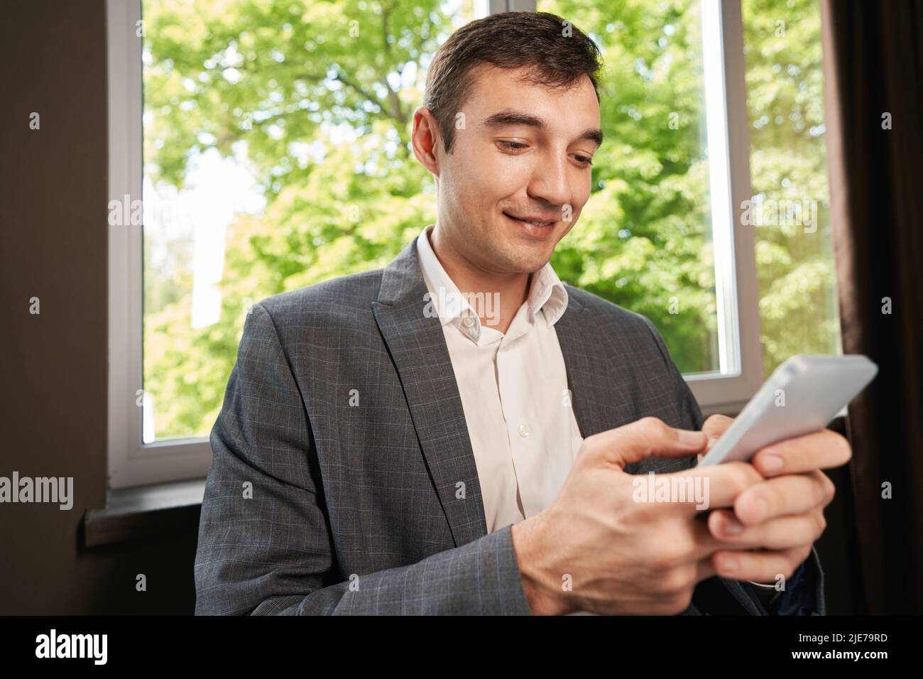 Man in suit texting message on smartphone at workplace Stock Photo - Alamy