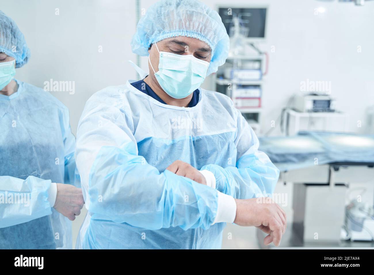 Senior surgeon putting on uniform for operation Stock Photo - Alamy
