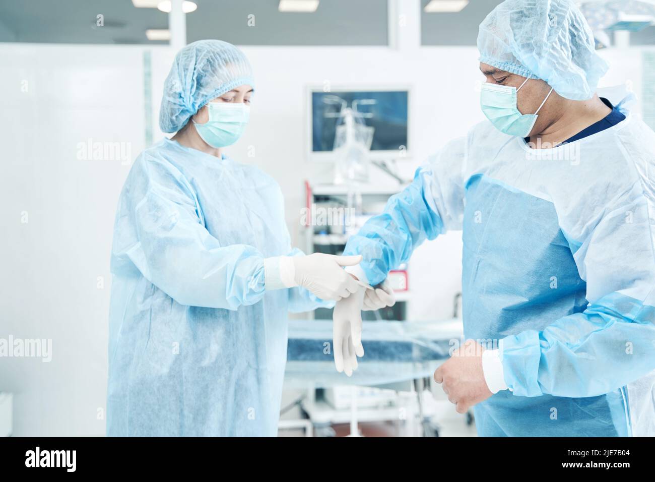 Professional surgeon getting ready for the operation with his nurse ...