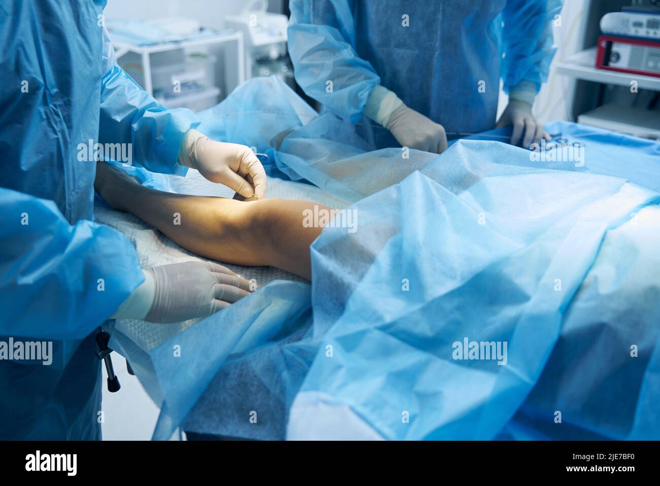 Two surgeons treating the leg of their patient Stock Photo - Alamy