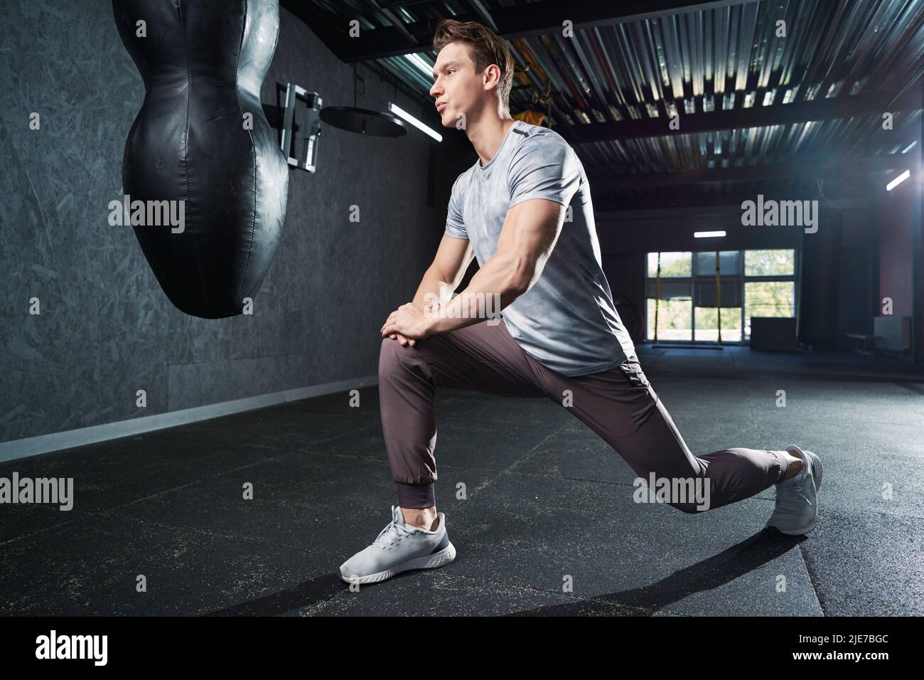Tranquil concentrated sporty guy stretching leg muscles Stock Photo - Alamy