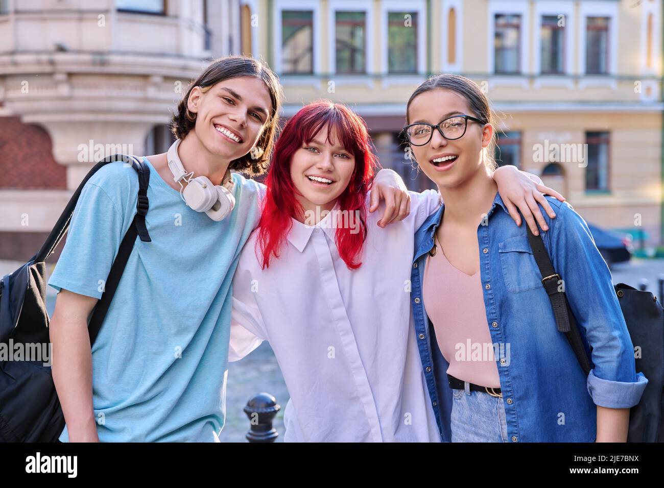 Happy smiling teenage friends hugging, looking at camera outdoor, on ...
