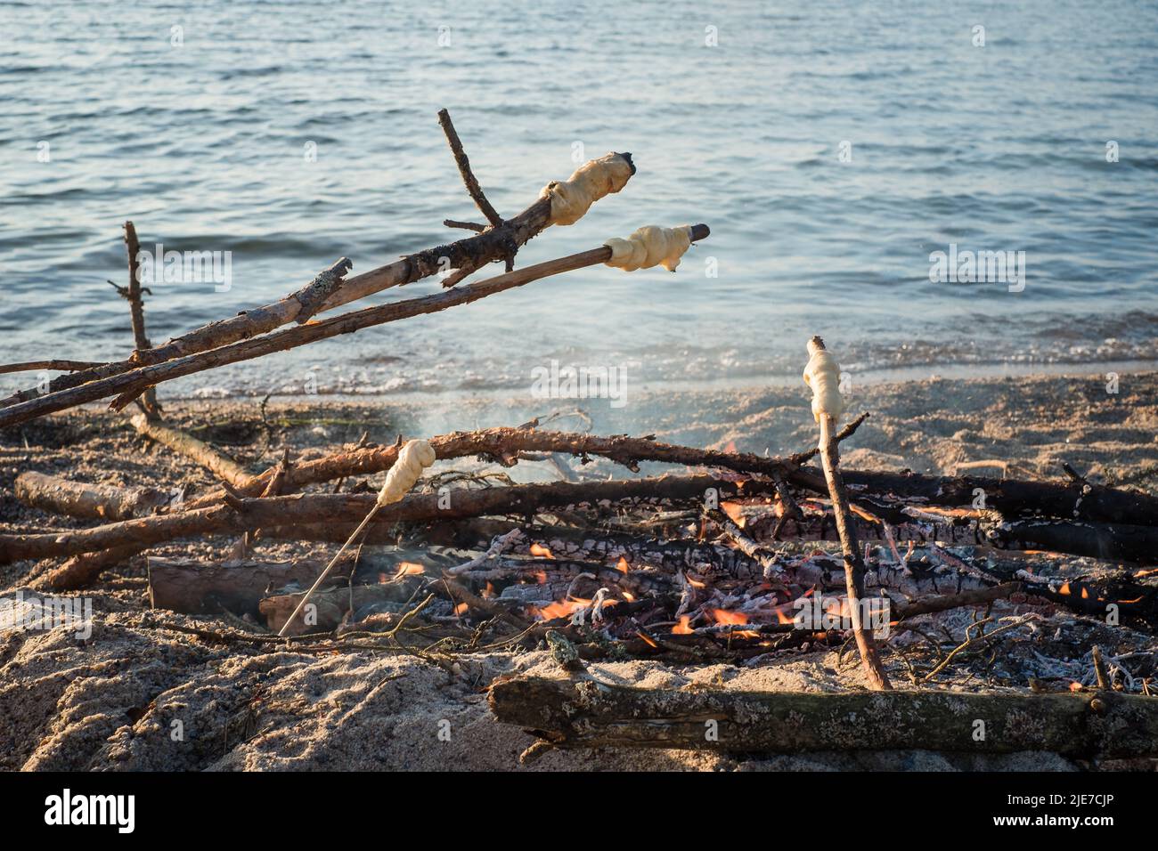 Stick bread cooked on campfire. Bread dough twisted on wooden stick and ...