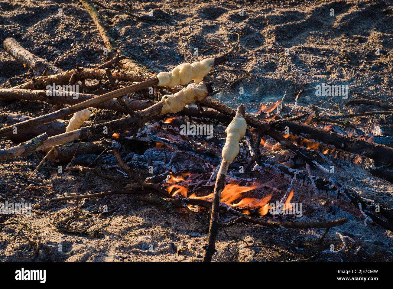 Stick bread cooked on campfire. Bread dough twisted on wooden stick and ...