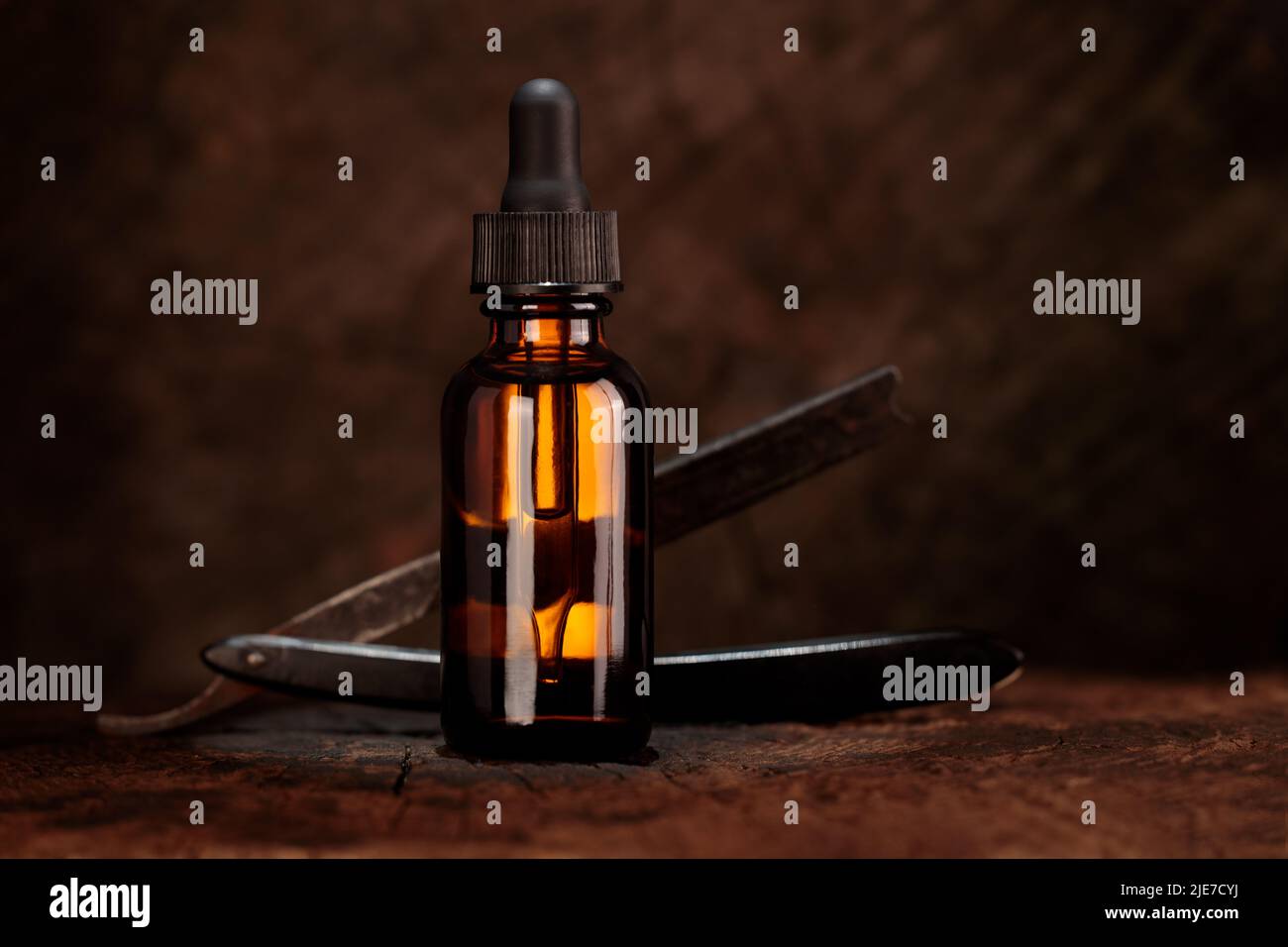 Amber beard oil bottle, dropper old razor and wood in background ...
