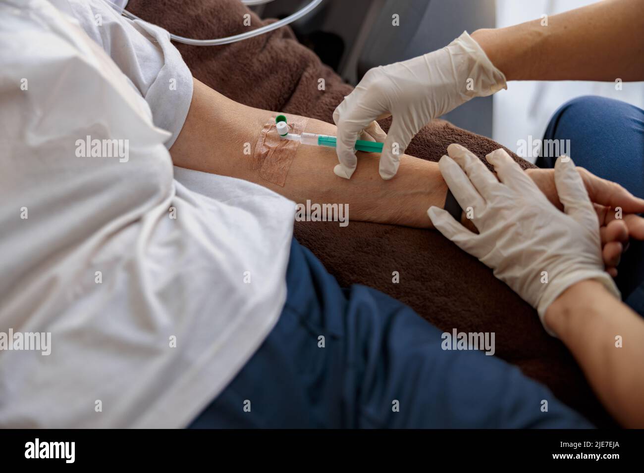 Nurse putting a drip in the arm of her patient in modern medical clinic ...