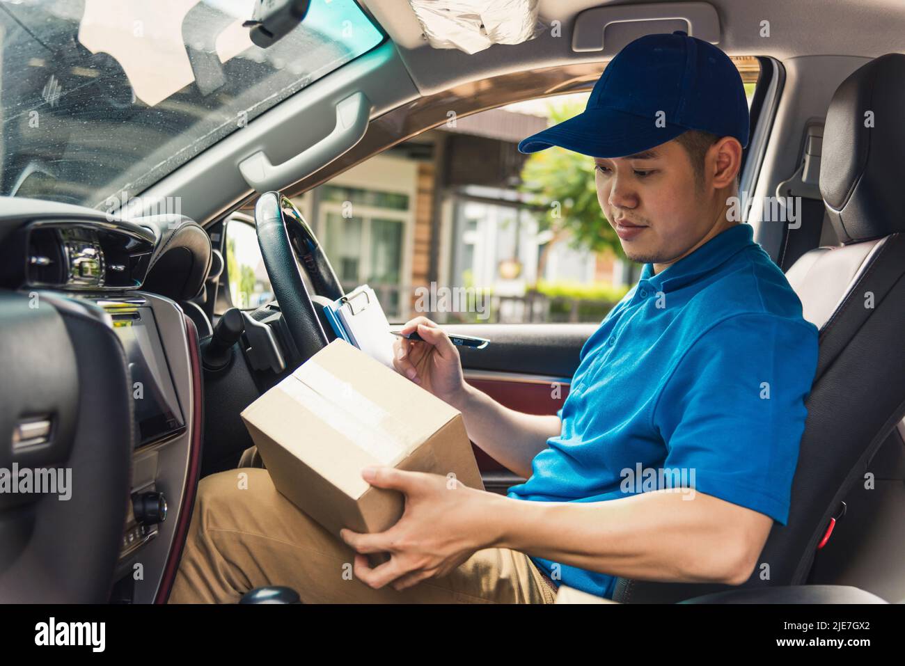 Asian young delivery man courier in uniform hold documents clipboard ...