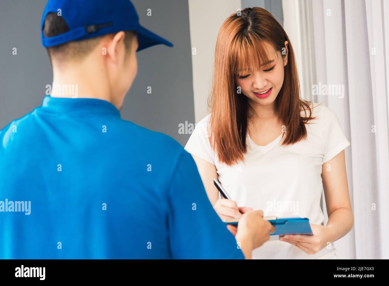 Asian beautiful customer young woman signing delivery in clipboard get ...