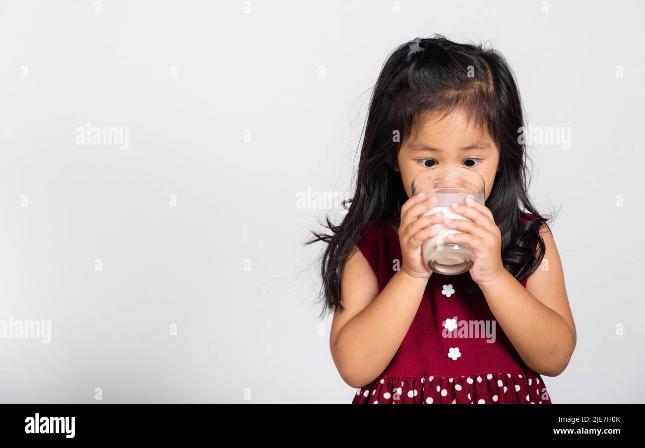 Little cute kid girl 3-4 years old smile holding milk glass he drinking ...