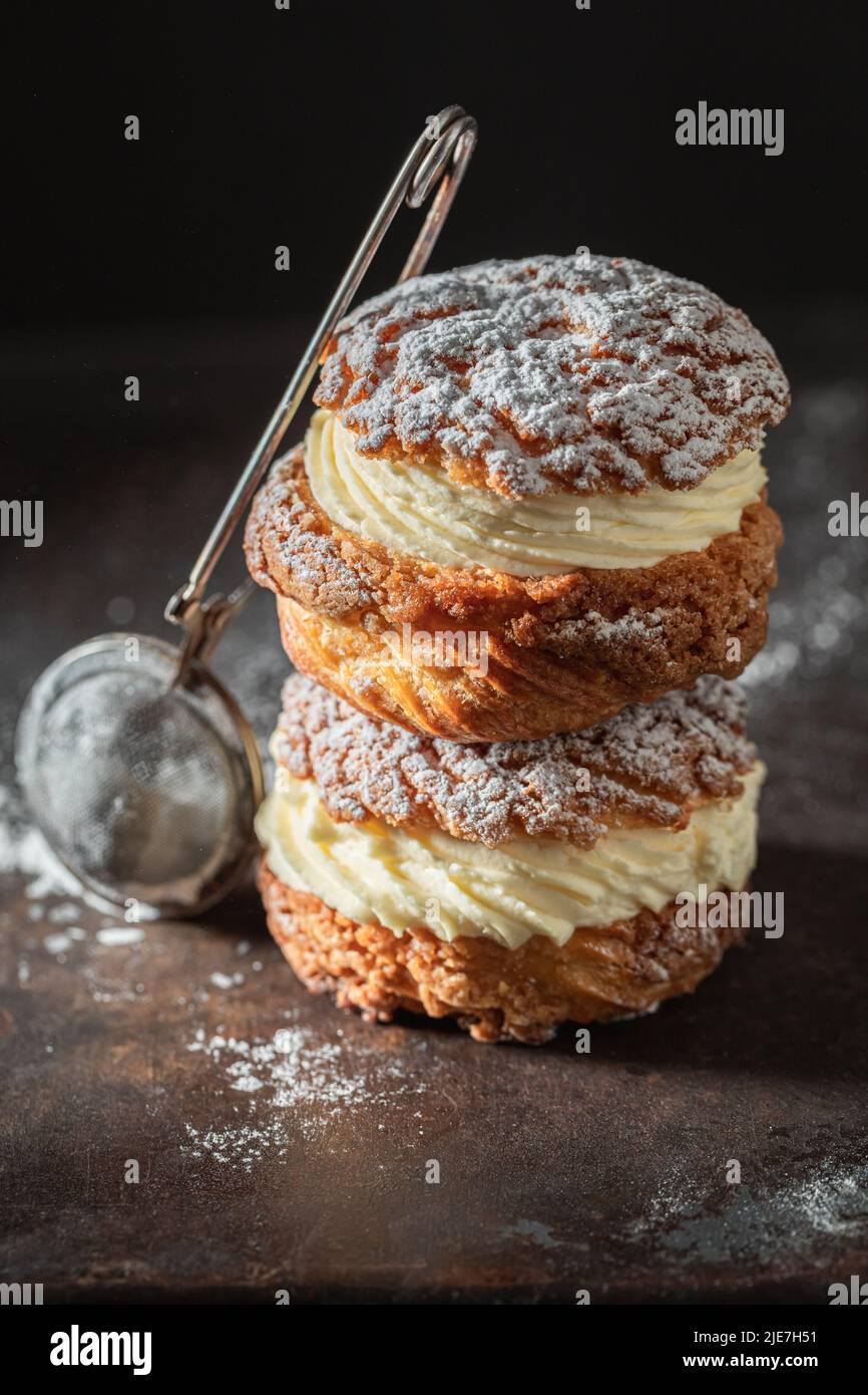 Delicious and fresh cream puffs with powdered sugar in strainer. Cream ...