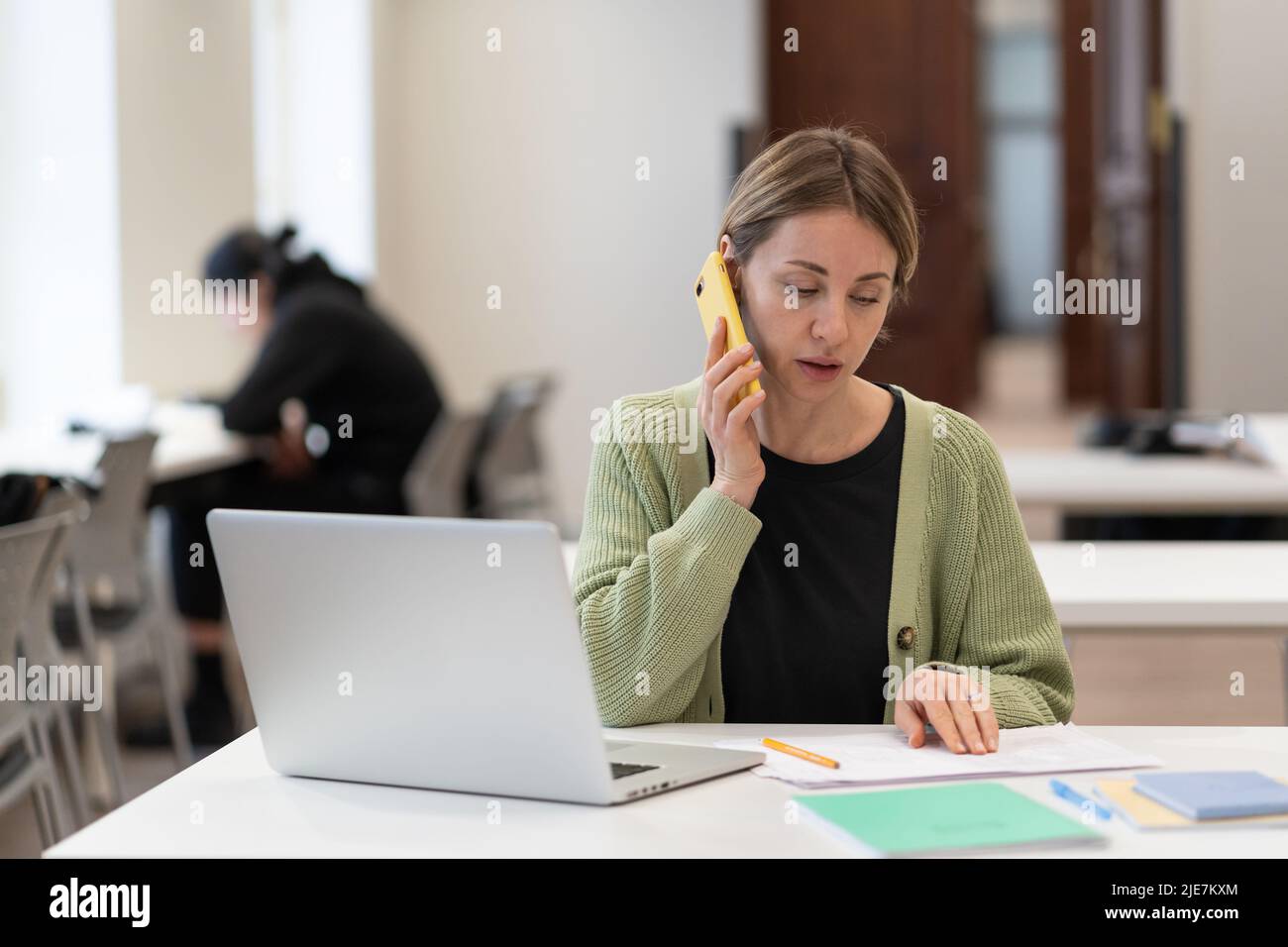 Middle-aged woman busy with documents talking on cellphone working in ...