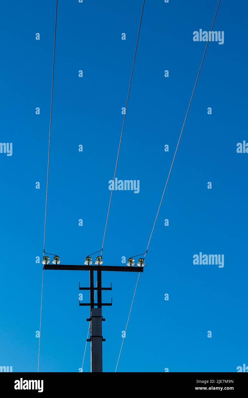 Top of a three-phase transmission line pole with insulators. Against ...