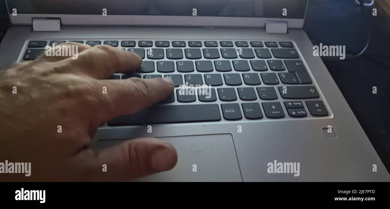 hand of a person typing on a gray pc with white letters Stock Photo - Alamy