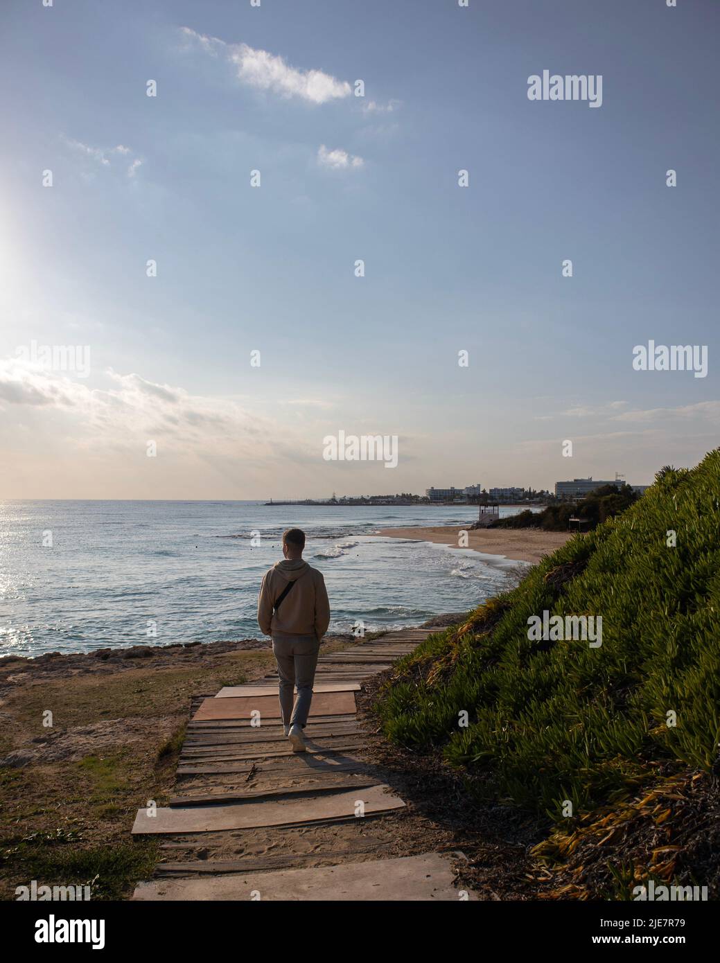 A man is walking on a wooden walkway to the beach in Ayia Napa, Cyprus ...