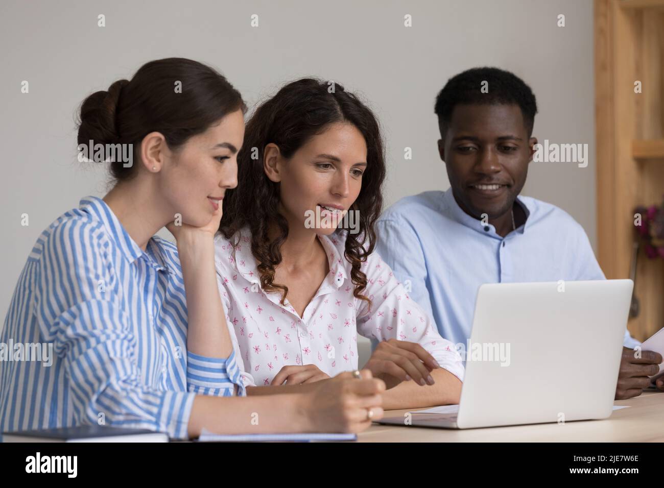 Three multiracial employees use laptop discuss online presentation ...