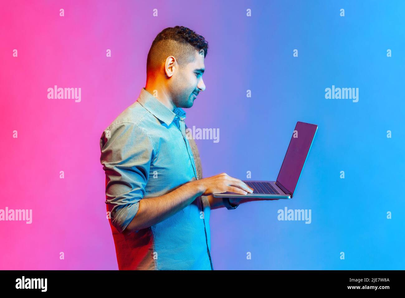 Side view of man in shirt holding laptop in hand and typing, blogger ...